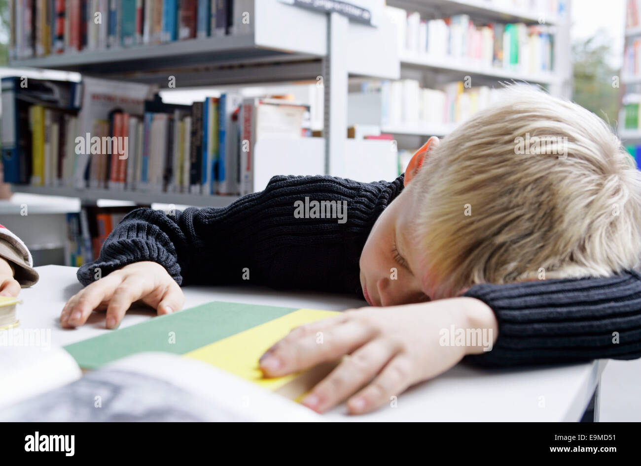 A boy taking a nap on a desk in a library Stock Photo - Alamy