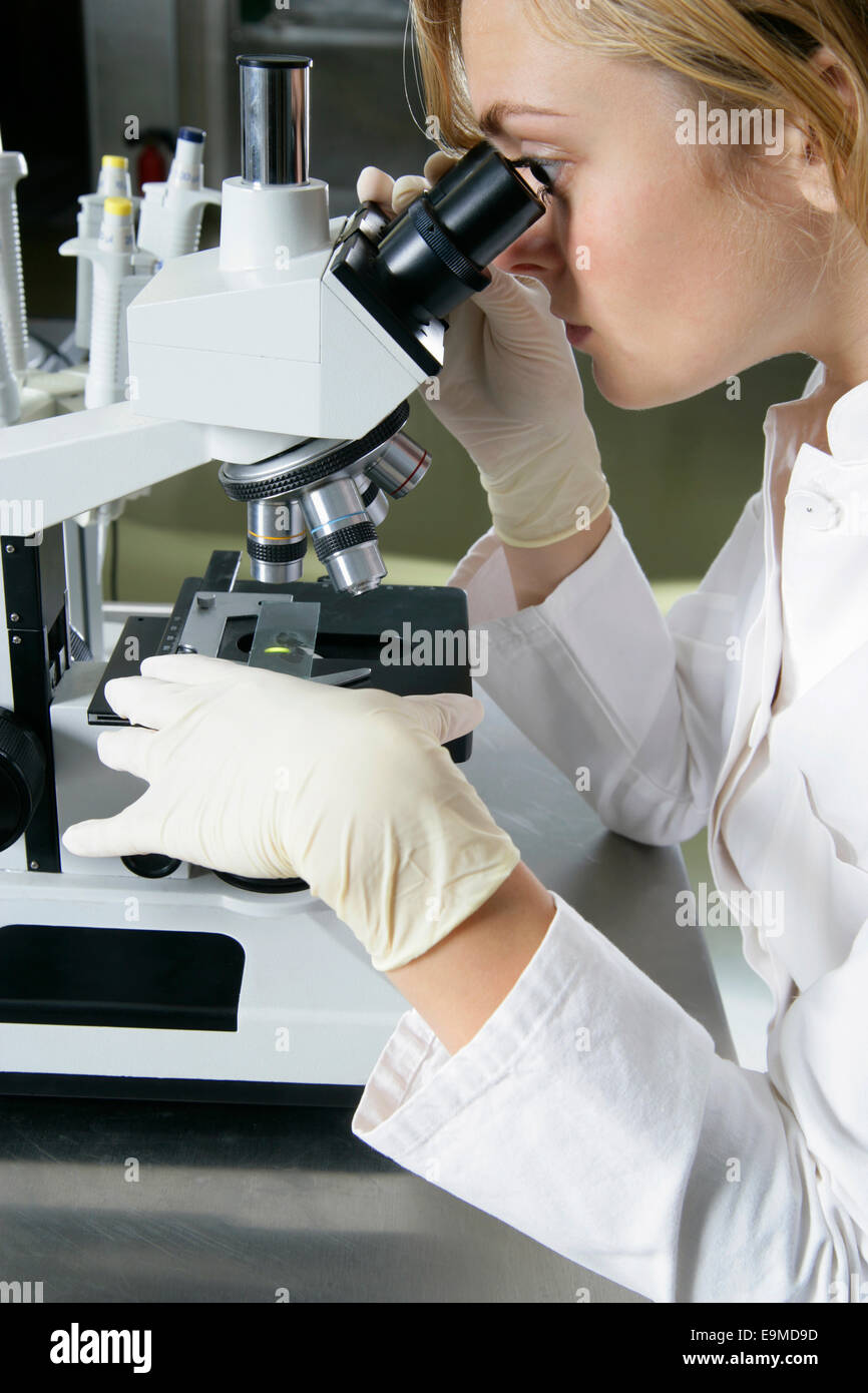 A woman looking through a microscope Stock Photo - Alamy