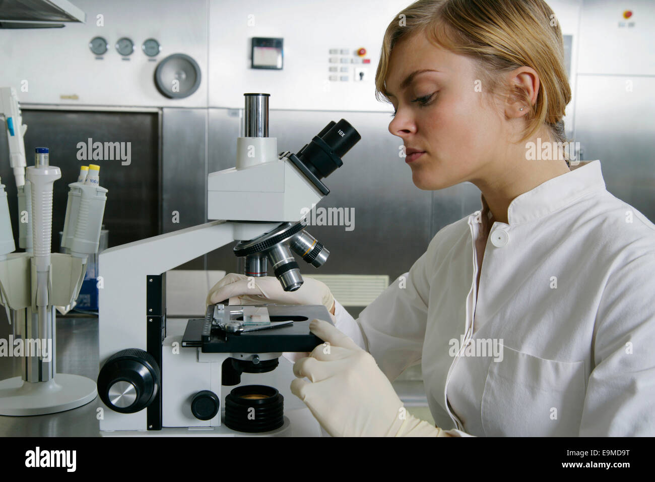 A woman looking through a microscope Stock Photo - Alamy