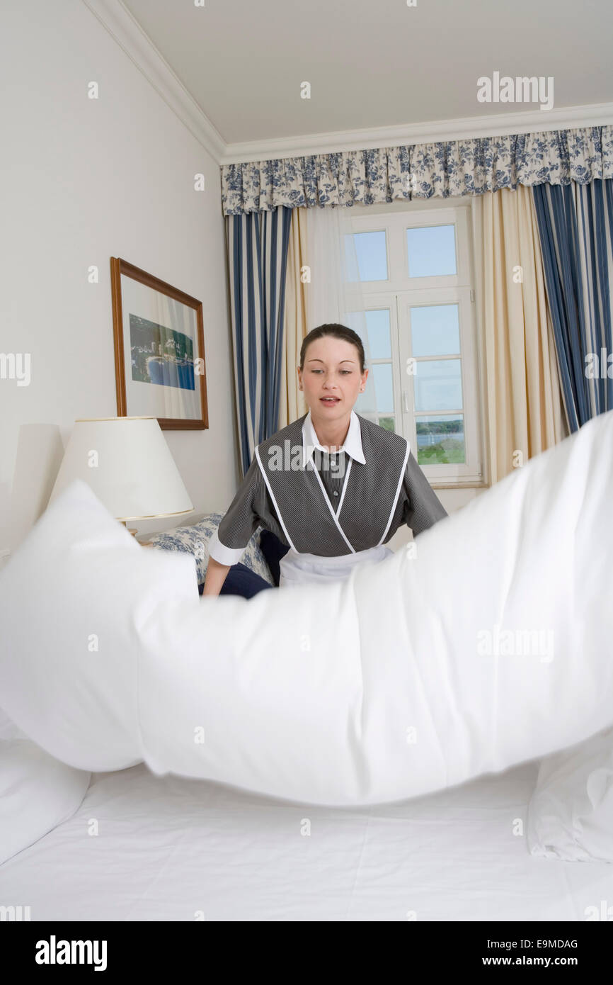 Uniformed maid making bed in hotel room Stock Photo - Alamy