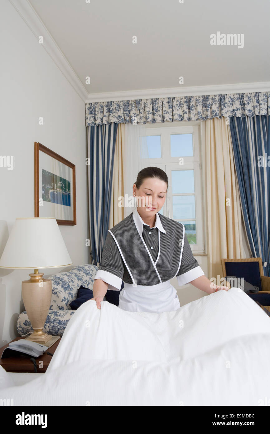 Uniformed maid making bed in hotel room Stock Photo - Alamy