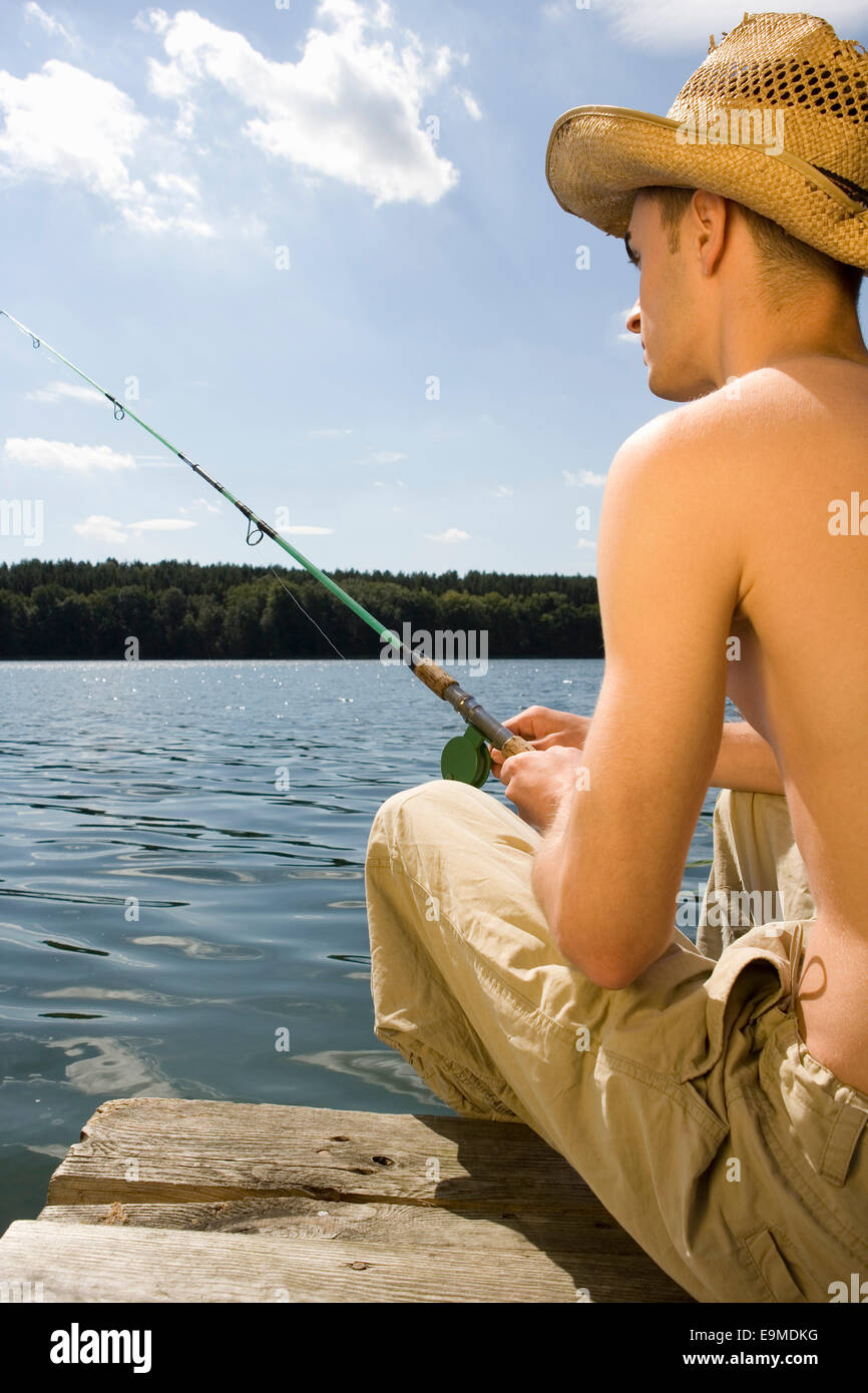 Young man fishing in lake Stock Photo - Alamy