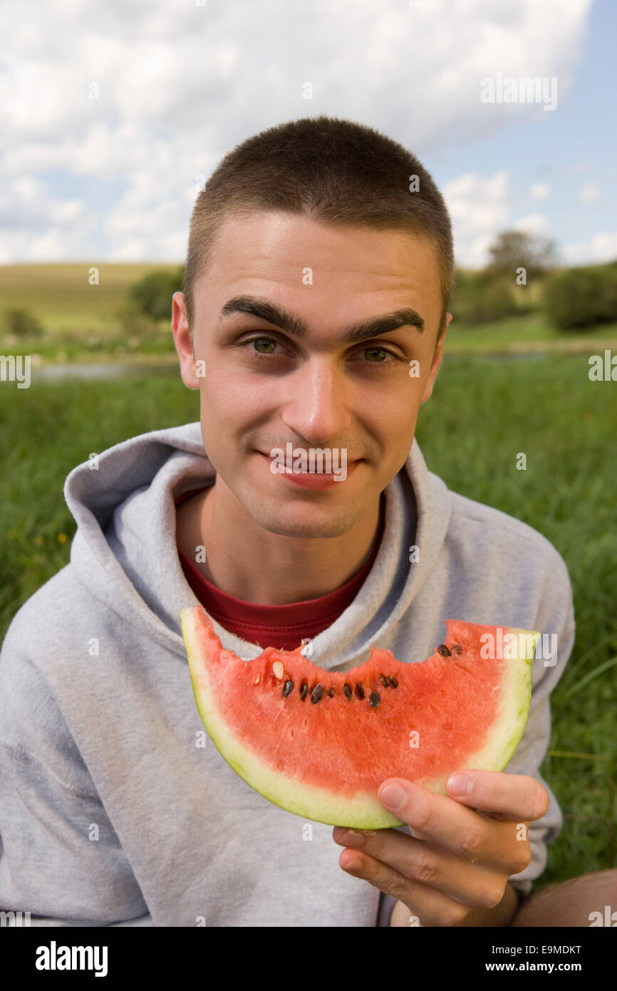 Portrait of young man eating watermelon Stock Photo - Alamy