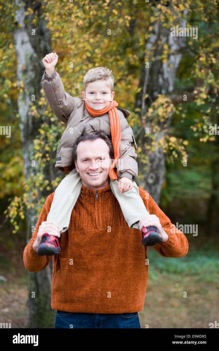 Son sitting on father’s shoulders in a park Stock Photo - Alamy
