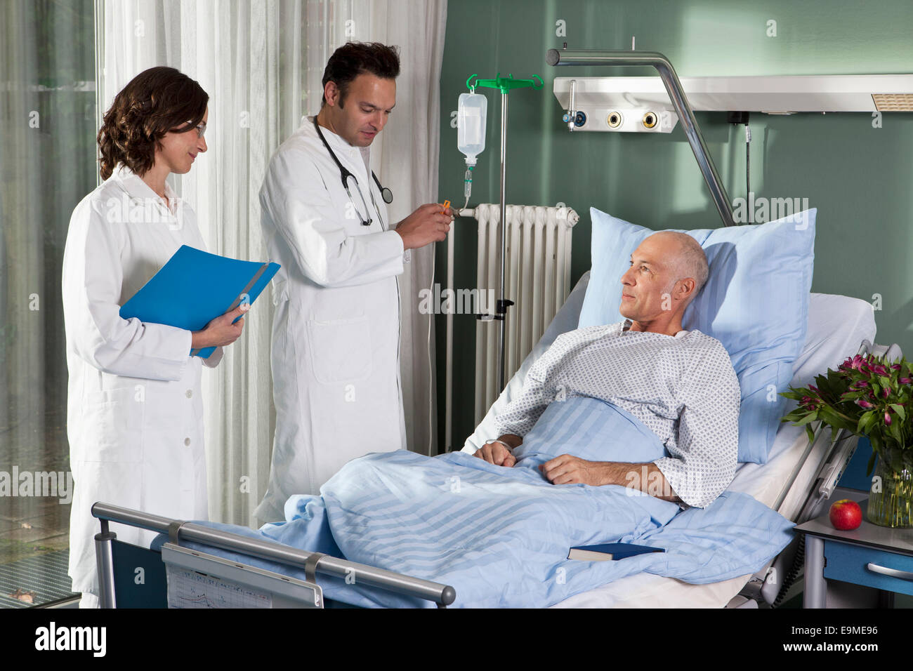 Two doctors with a male patient in a hospital ward Stock Photo - Alamy