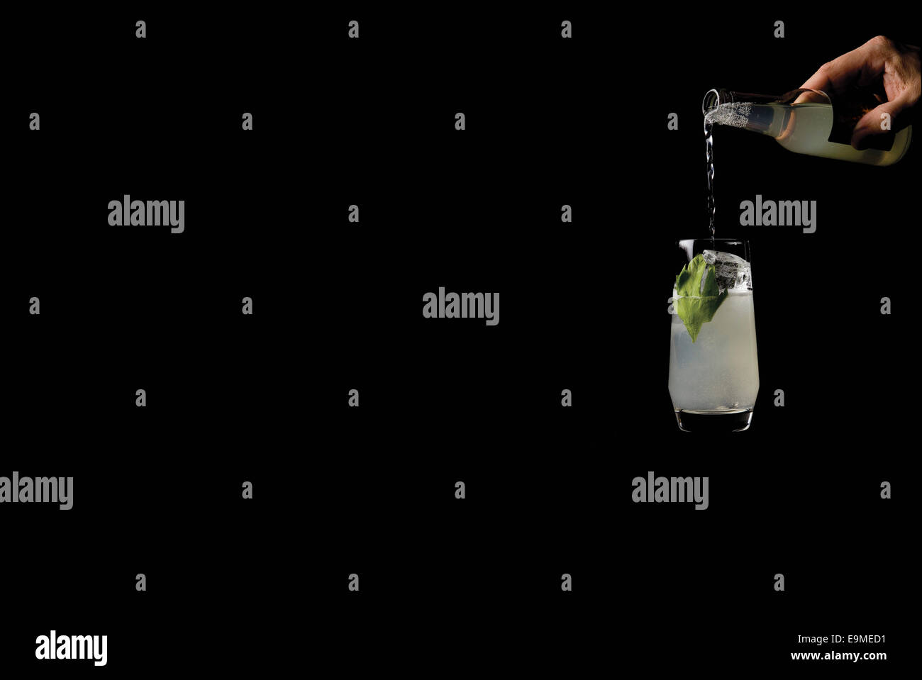 Hand pouring cocktail in glass over black background Stock Photo - Alamy