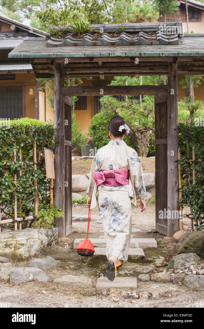 Full length rear view of woman in traditional wear entering gateway ...