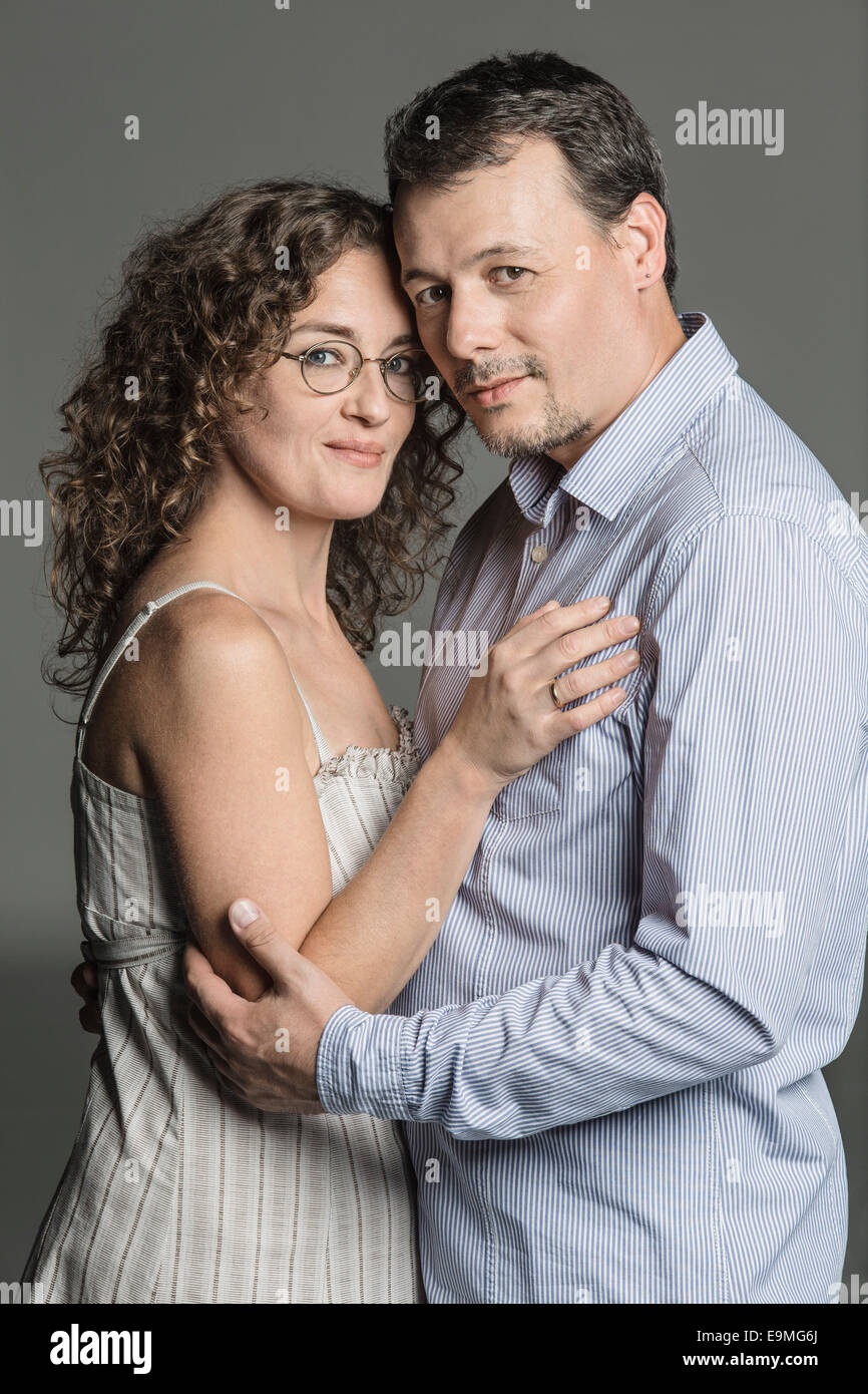 Side view portrait of loving couple embracing against gray background ...