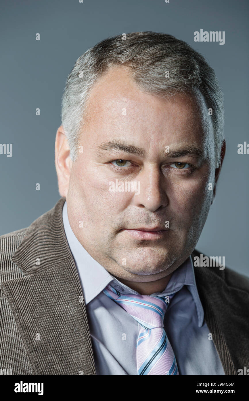Portrait of serious businessman against gray background Stock Photo - Alamy
