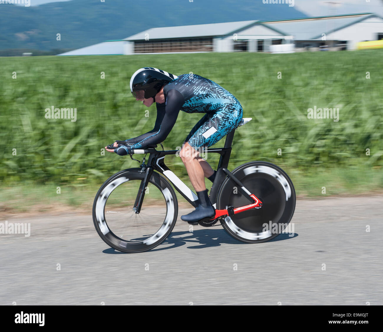 Full length side view of cyclist riding bicycle on country road against ...