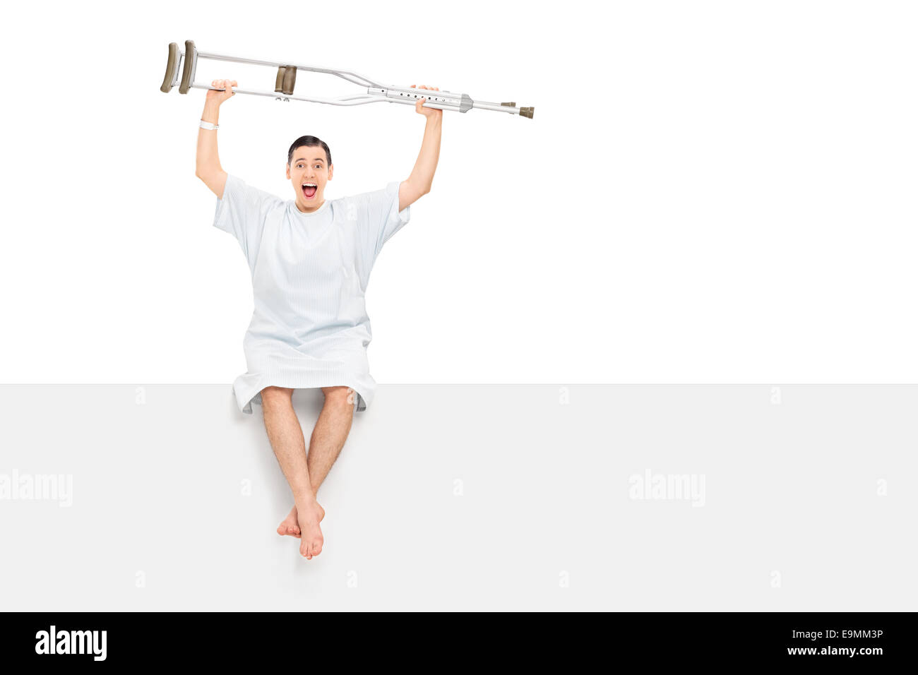 Overjoyed male patient raising his crutches in the air seated on a ...