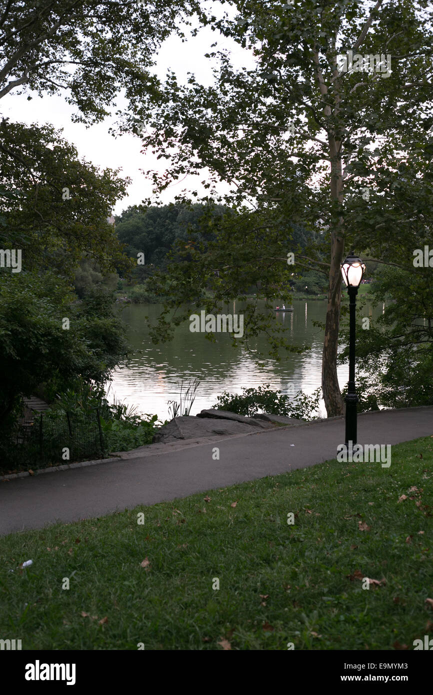 A path along the lake, lit by a street light in Central Park, New York ...