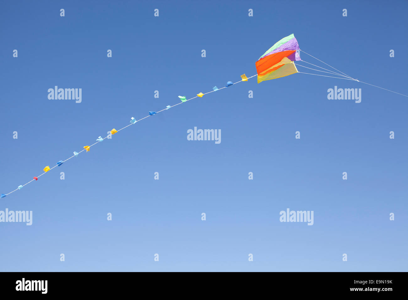 Colourful kite flying in the wind in front of clear blue skies Stock ...