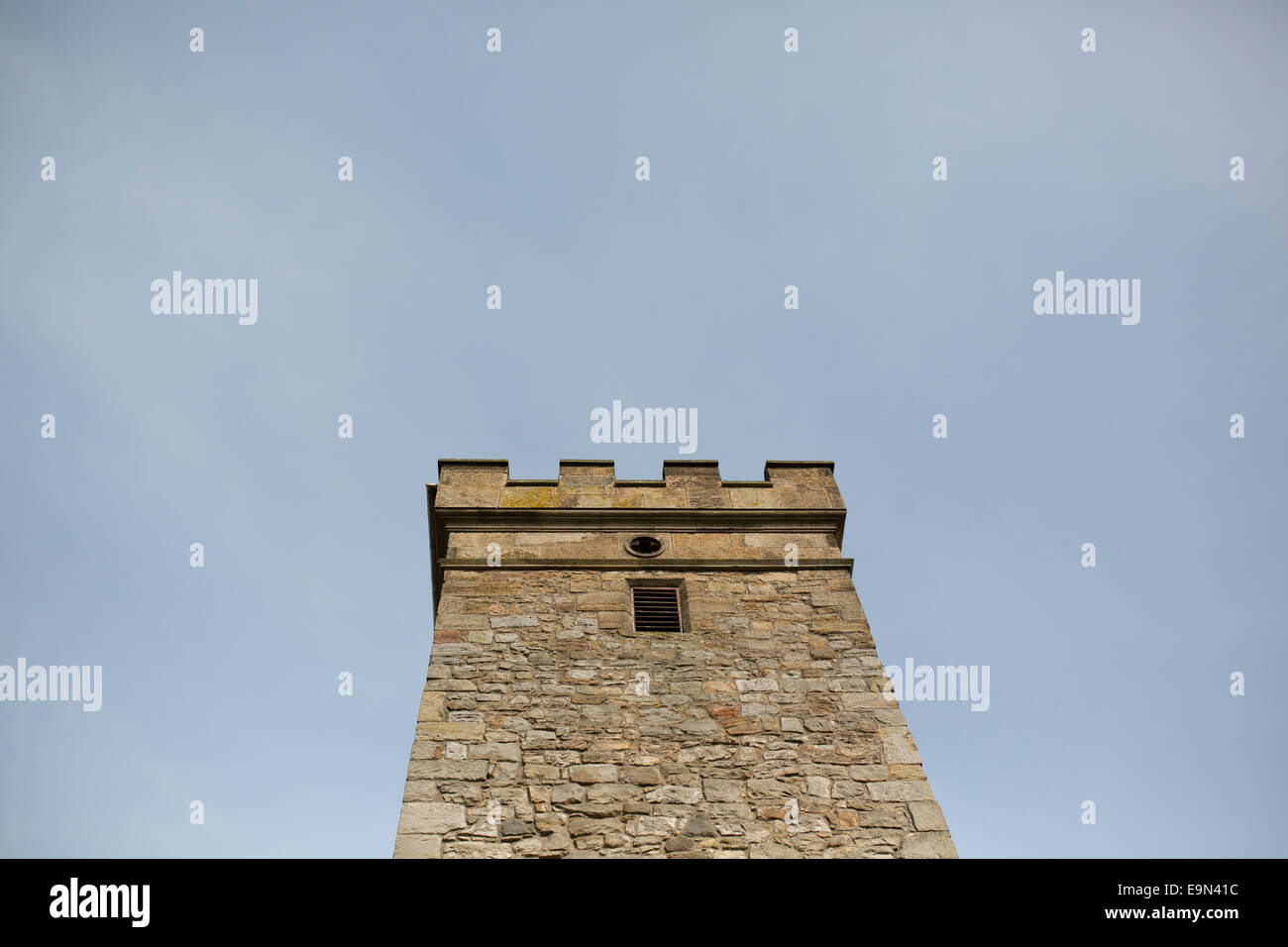 The stone spire of Cramond Kirk in Edinburgh set against a blue and ...