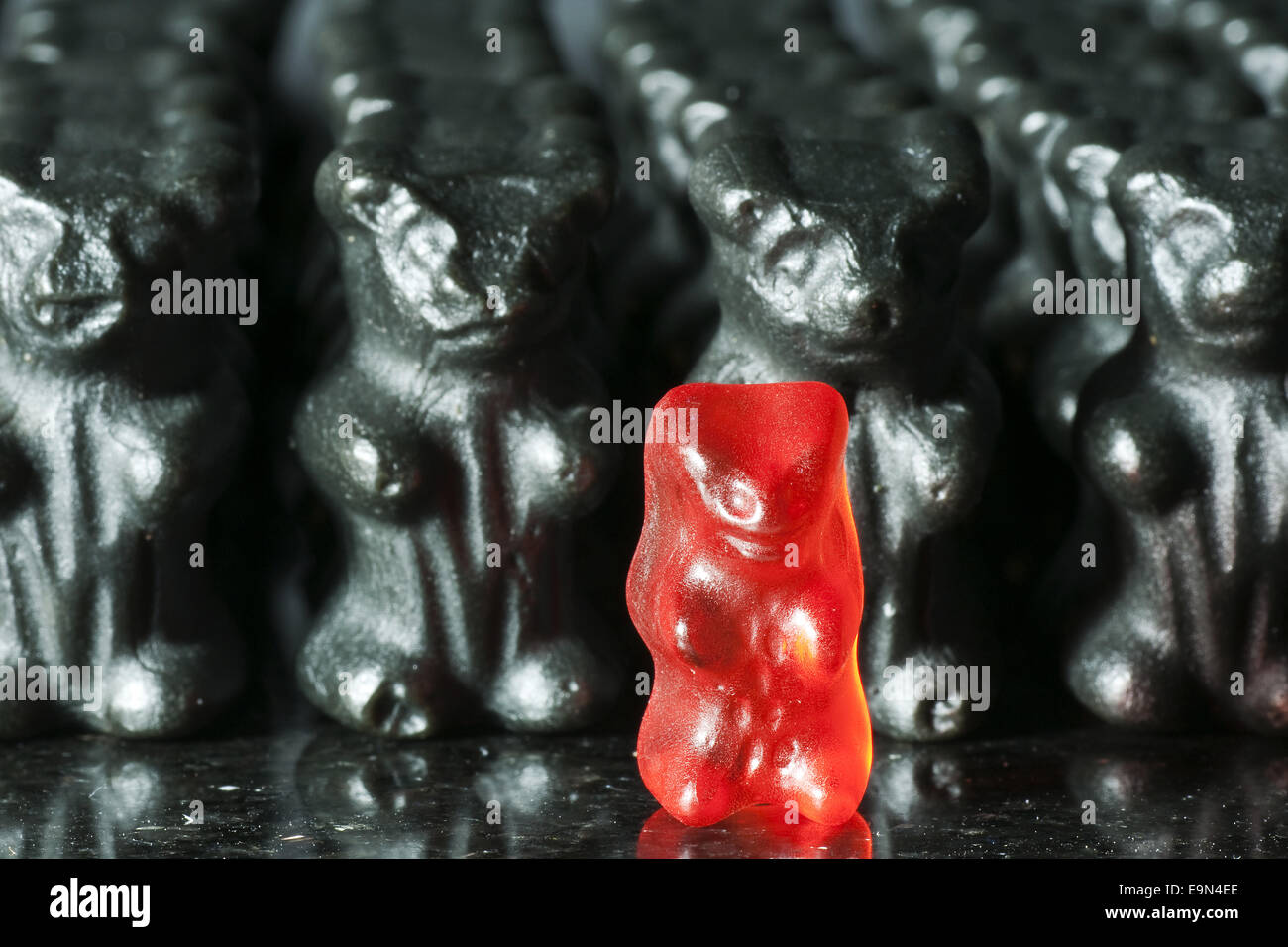 Lines of black gummi bears and a red chief Stock Photo - Alamy