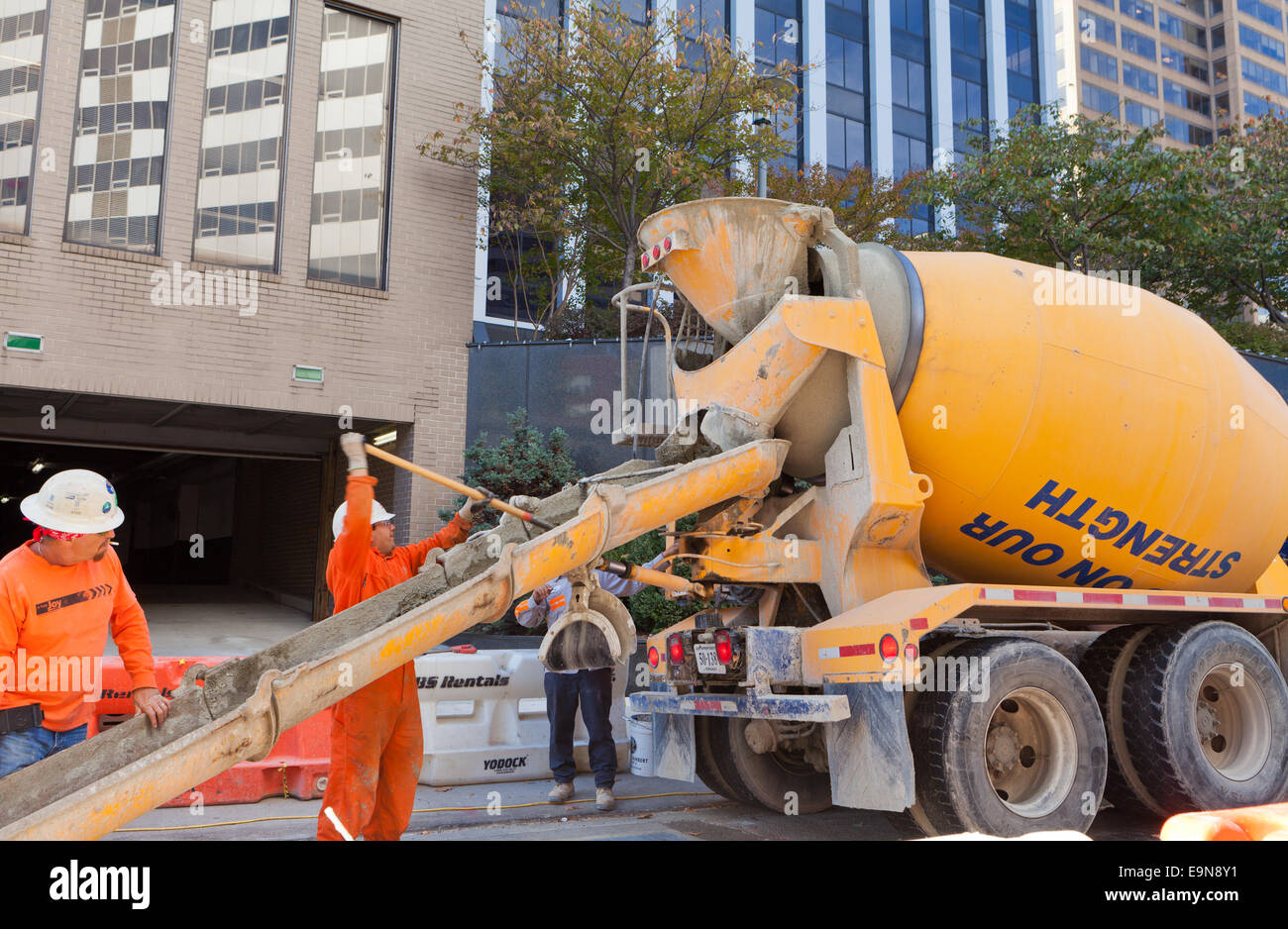 Municipal workers dumping concrete mix on roadside construction site ...