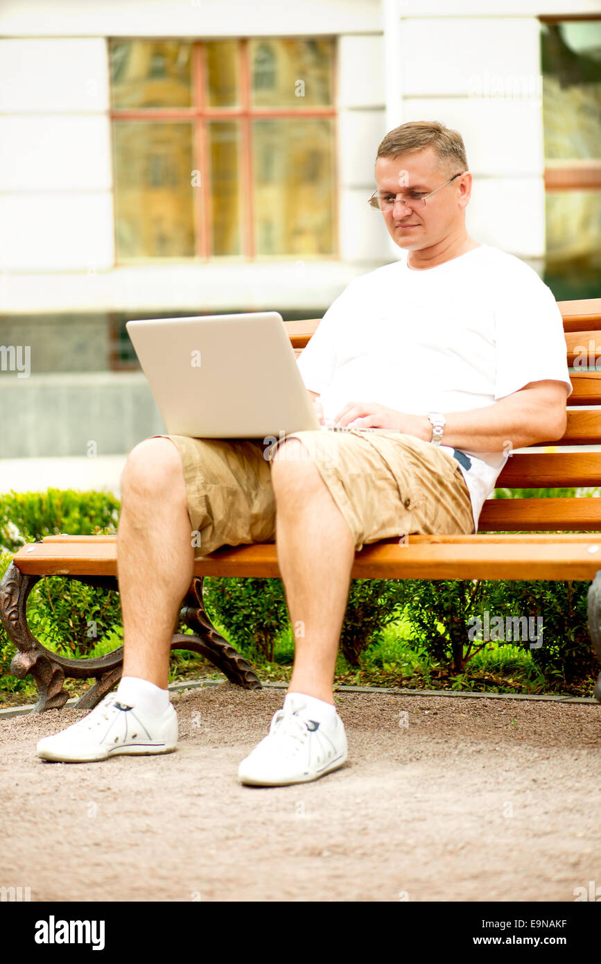 Man with laptop sitting on bench Stock Photo - Alamy