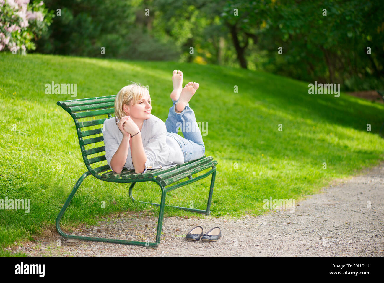 Young woman laying on bench Stock Photo - Alamy