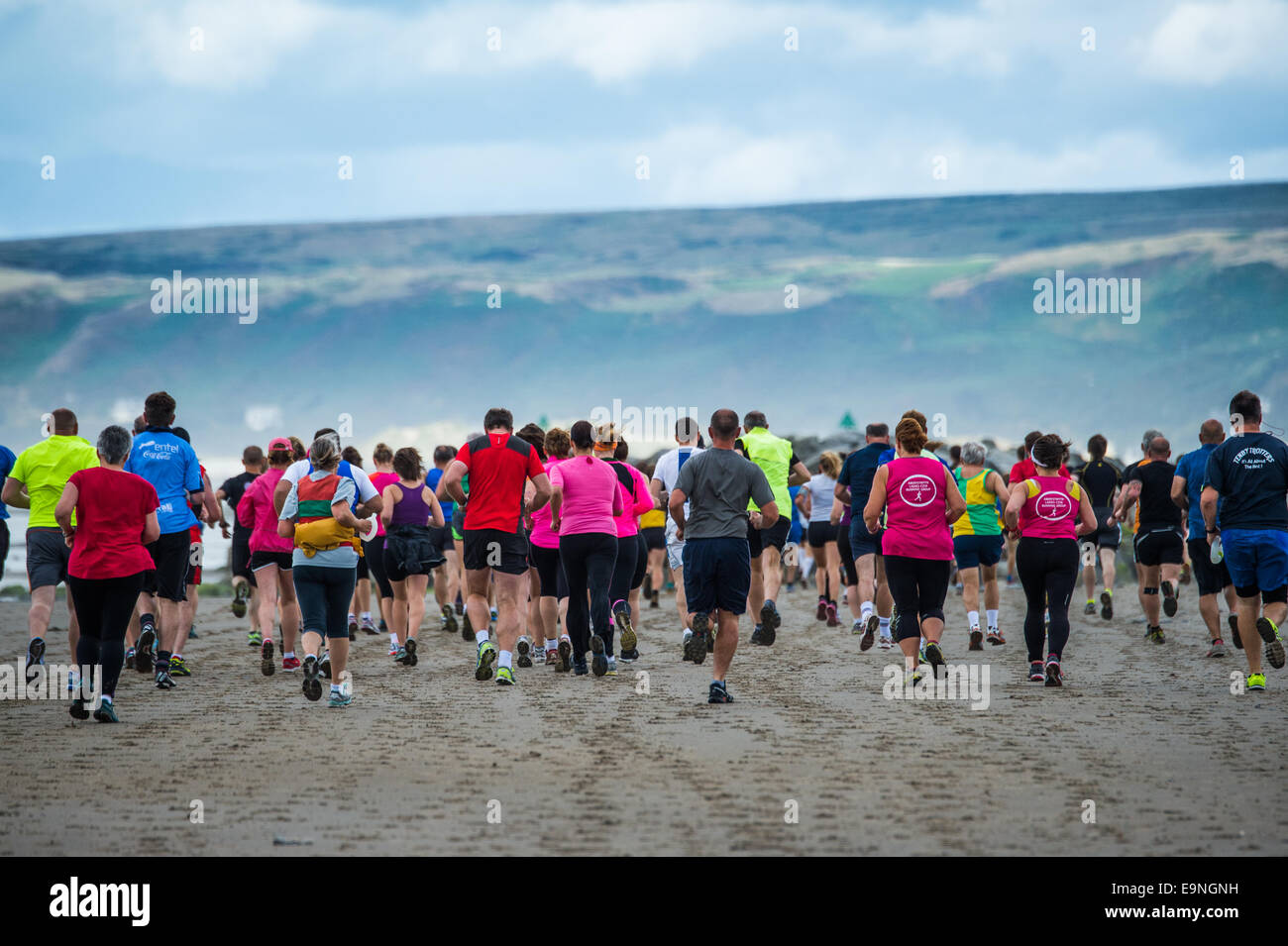 Rear view of a crowd of people competing running in a 10k race on the ...
