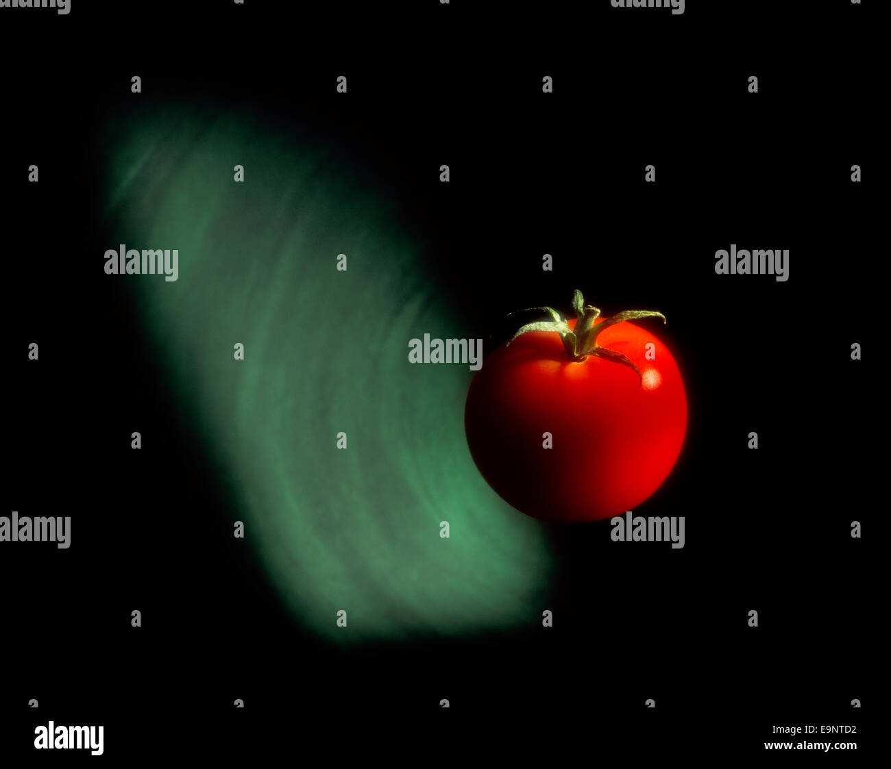 Simple single tomato against green background with shading to emphasise ...