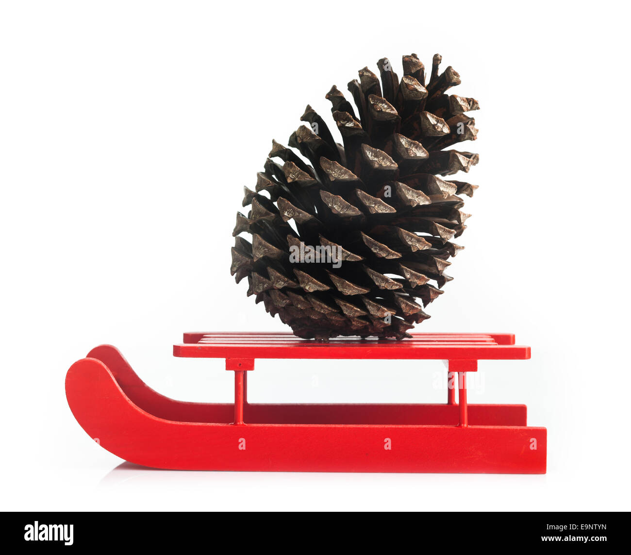 Wooden red sled with brown pine cone on white background Stock Photo ...