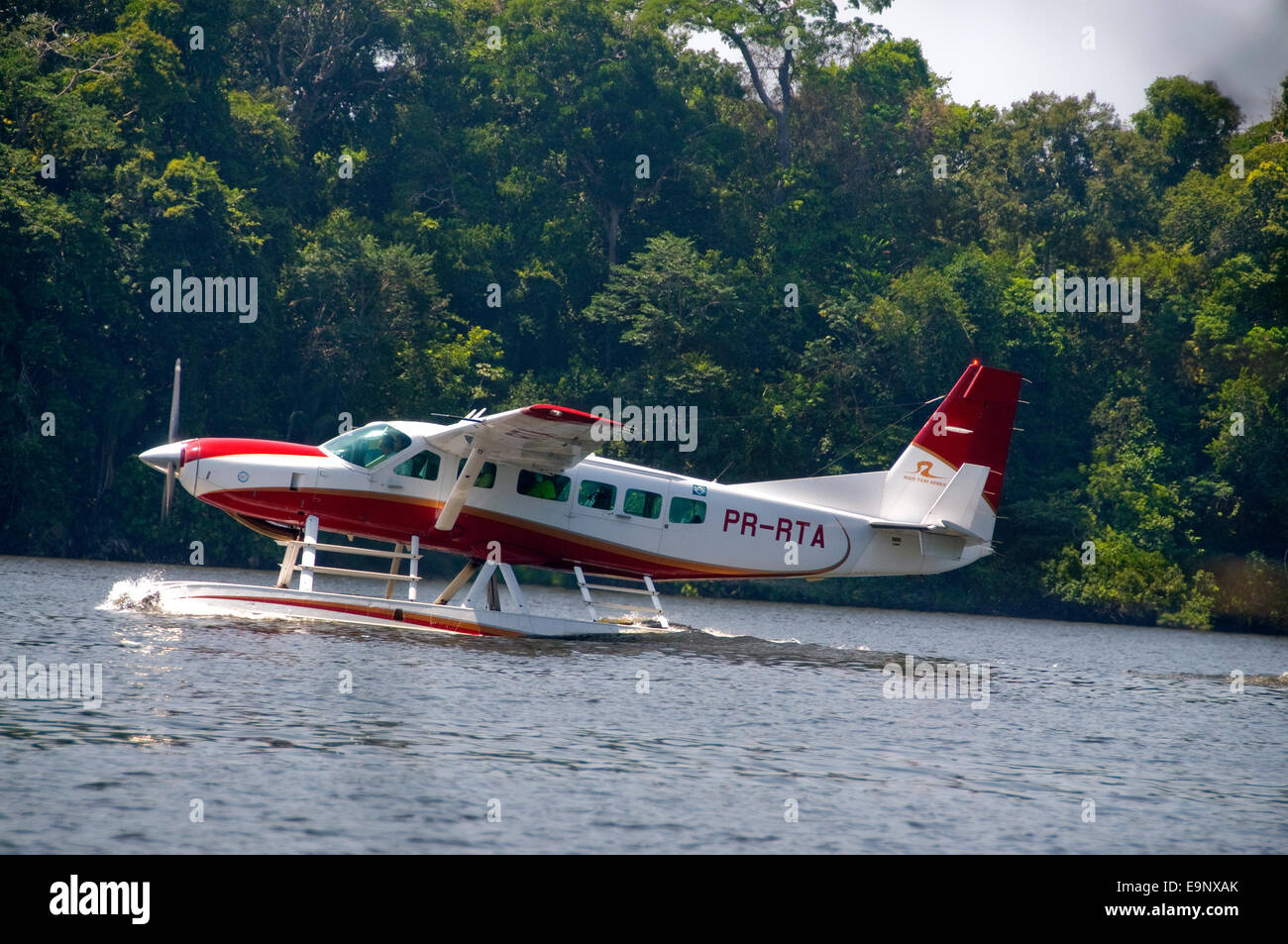 A Caravan float plane unloads gear and passengers into a small canoe on ...
