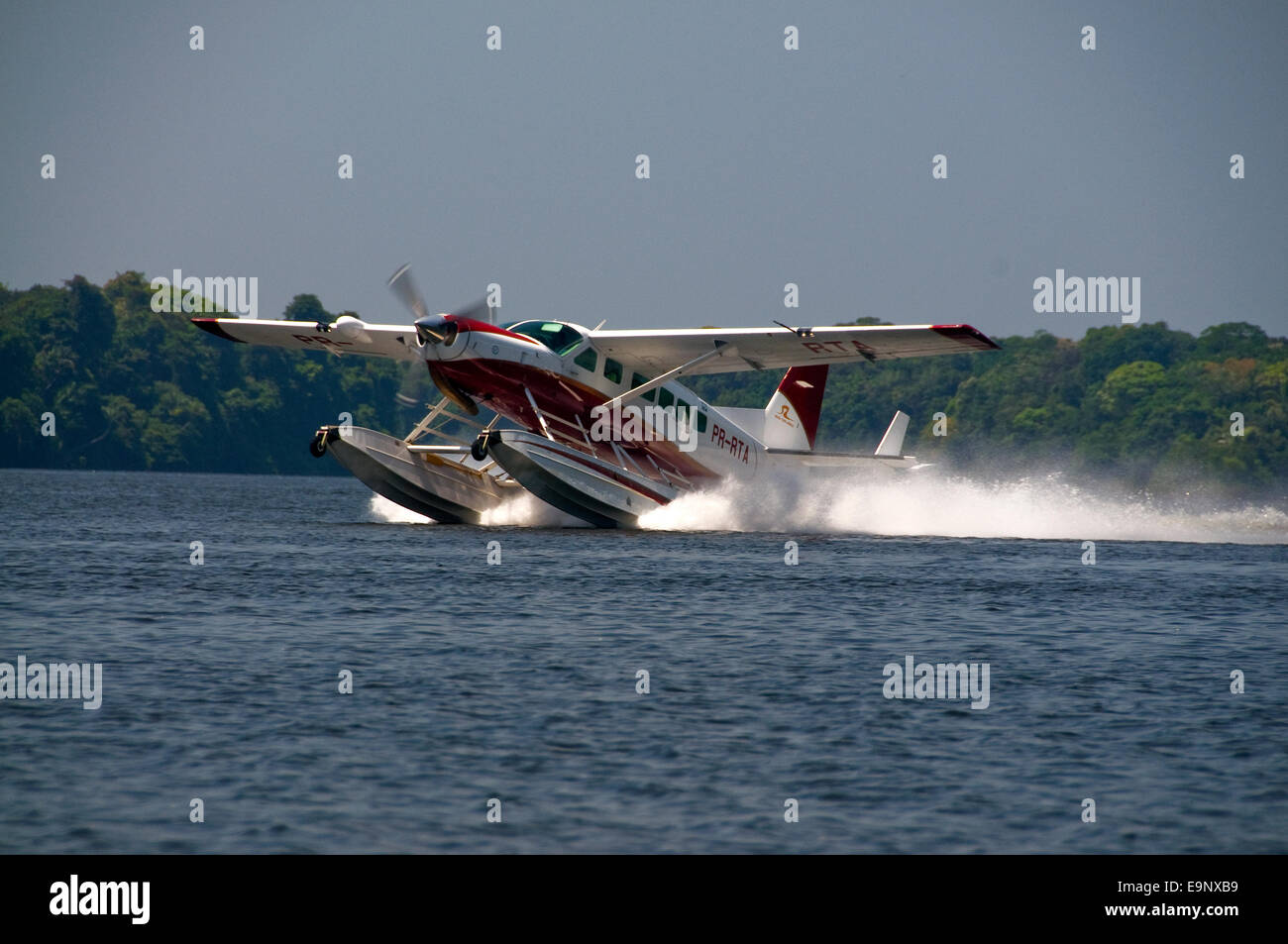 A Caravan float plane unloads gear and passengers into a small canoe on ...
