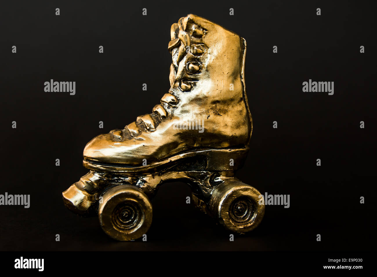 golden roller skate with high heel isolated against black background ...
