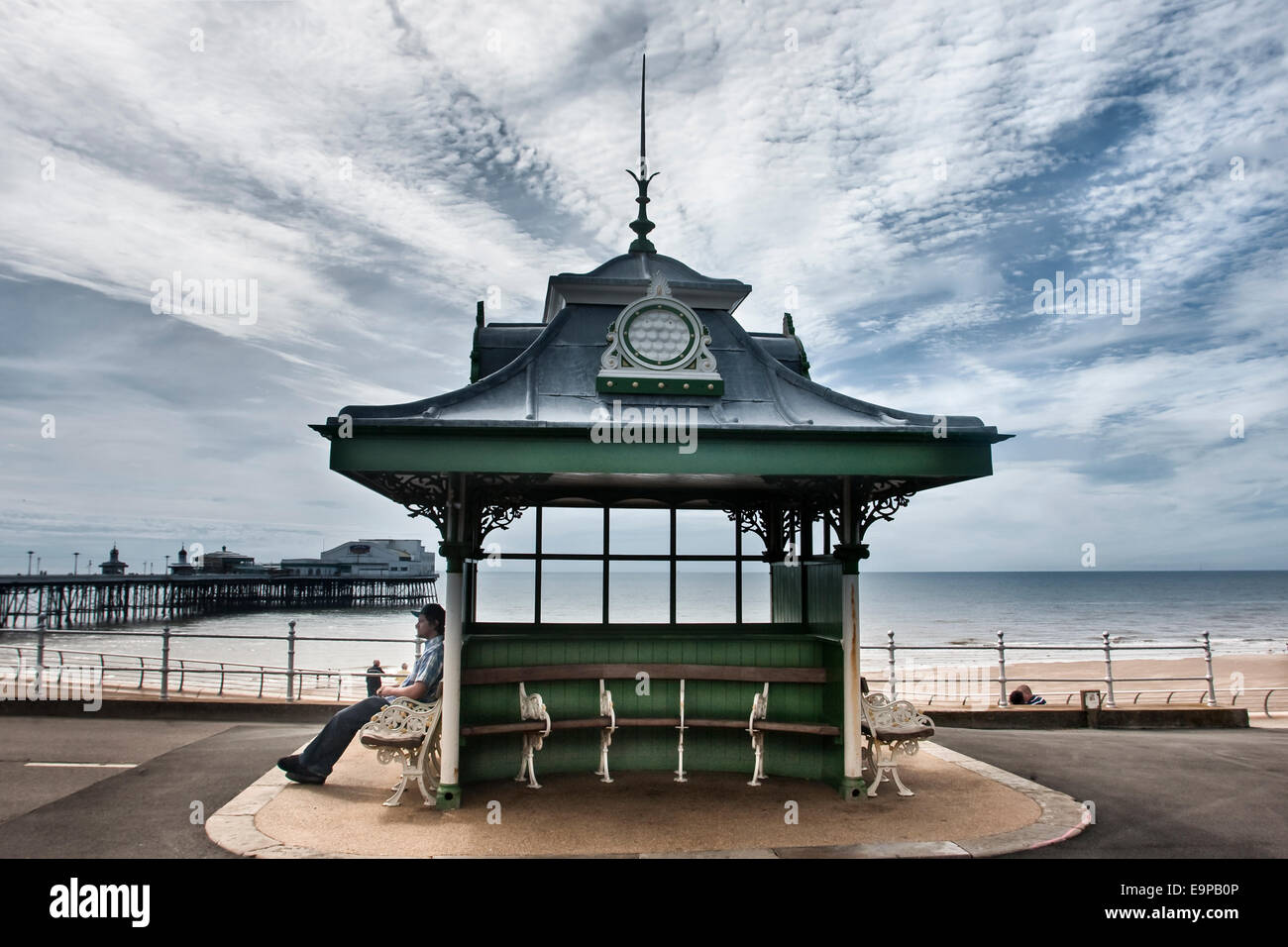 Man sitting in Blackpool wind shelter Stock Photo - Alamy