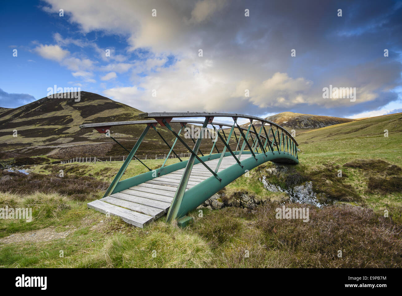 Metal footbridge over river in glen, in evening sunlight, Clunie Water ...
