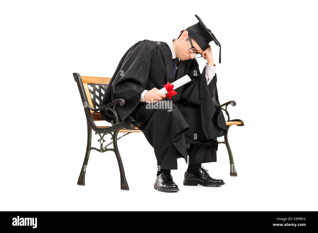 Sad graduate student sitting on a wooden bench isolated on white ...