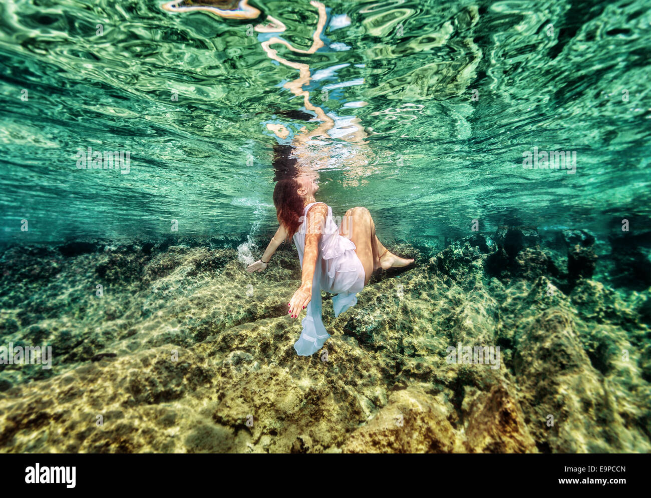 Dancing underwater, beautiful young female swimming in the sea near ...