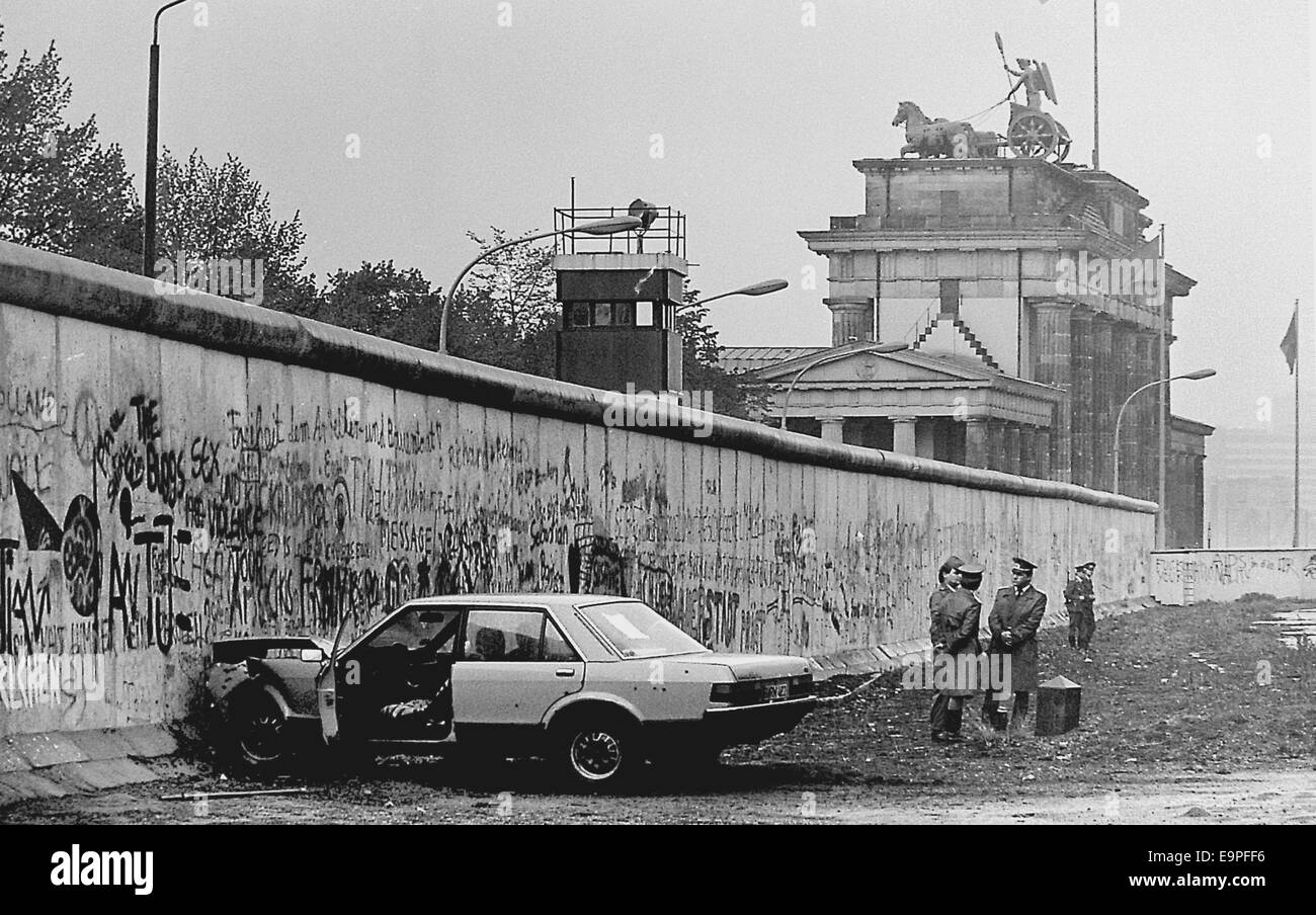 A destroyed car stands in front of the Berlin Wall at the Brandenburg ...