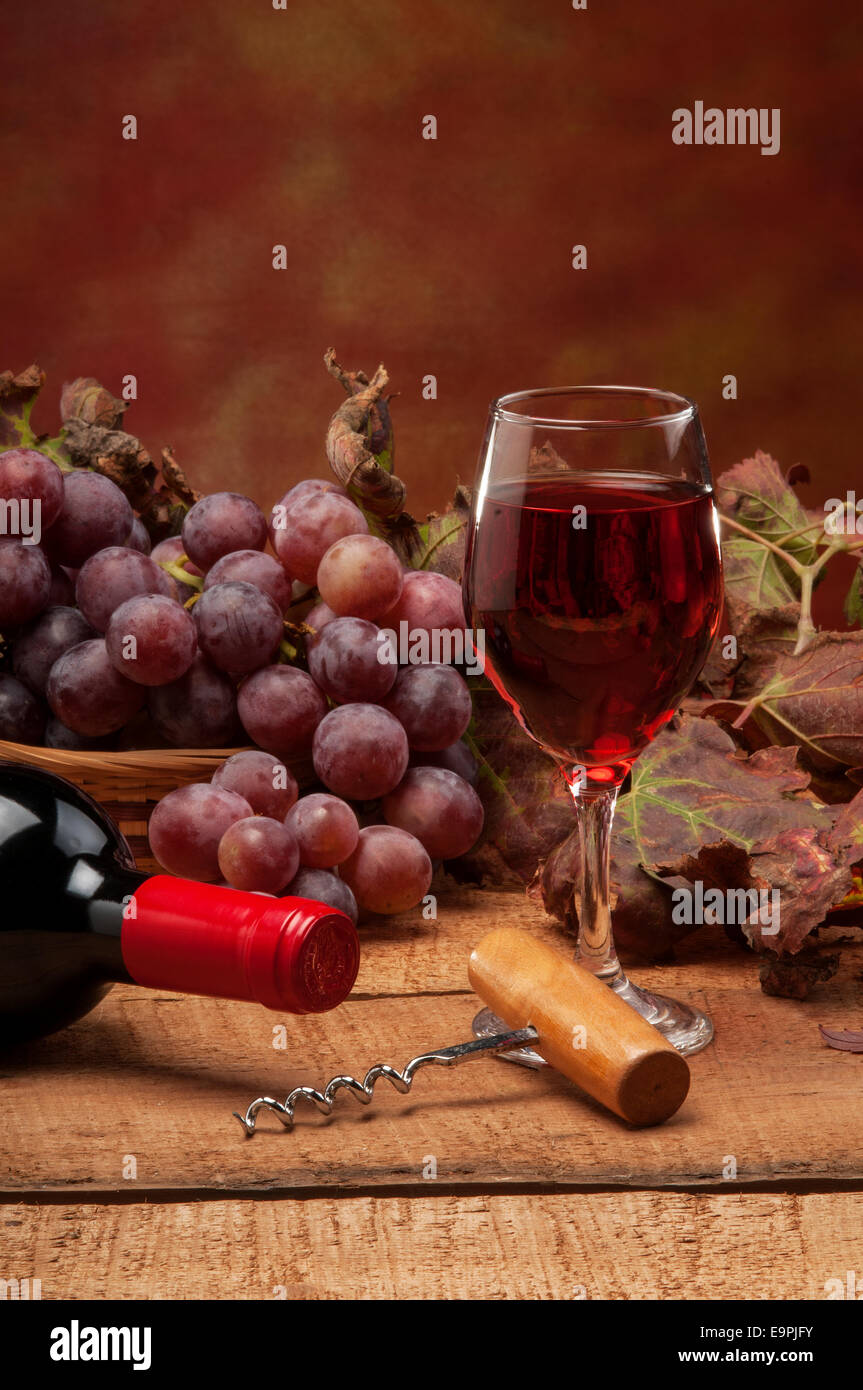 An old table with a bottle of wine, vine leaves, and red grapes Stock ...