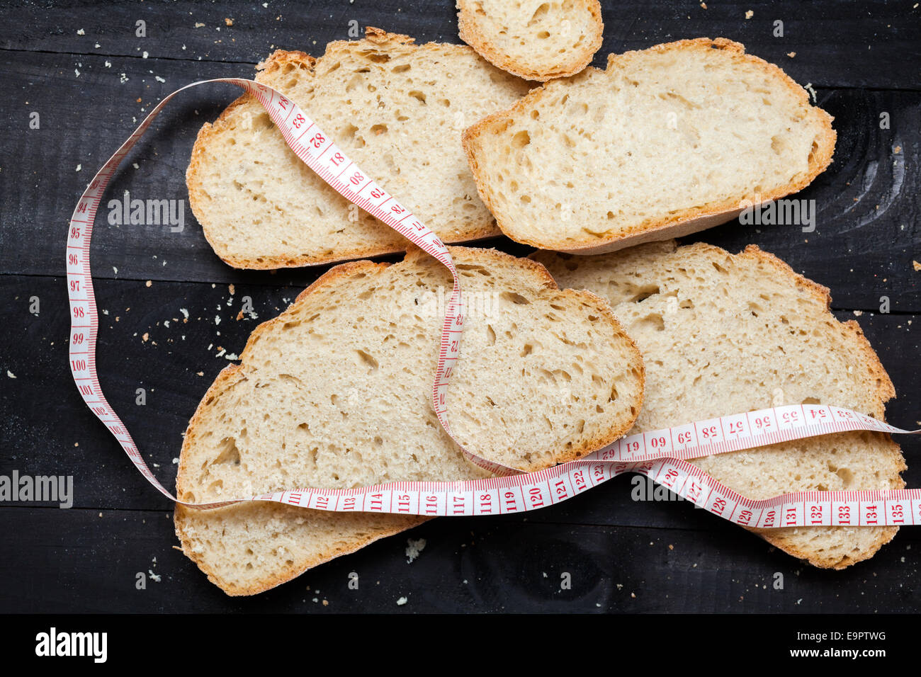Bread slices on black wooden table with tape measure Stock Photo - Alamy