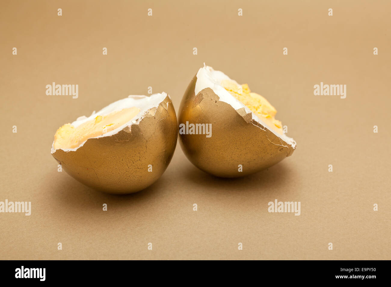 Boiled egg cut in two pieces, painted gold over beige background Stock ...