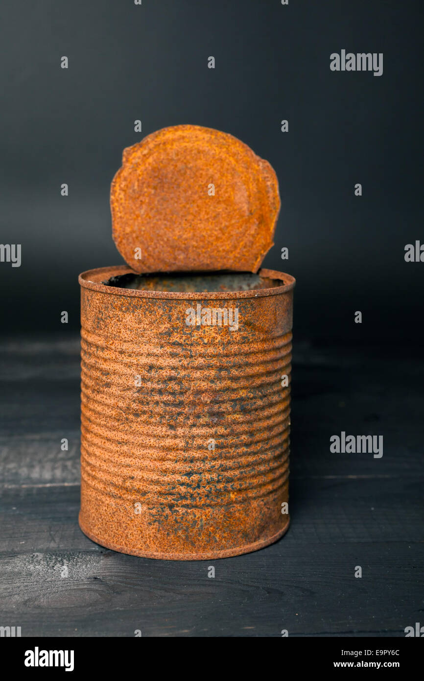 Old rusty tin can on dark wooden background Stock Photo - Alamy
