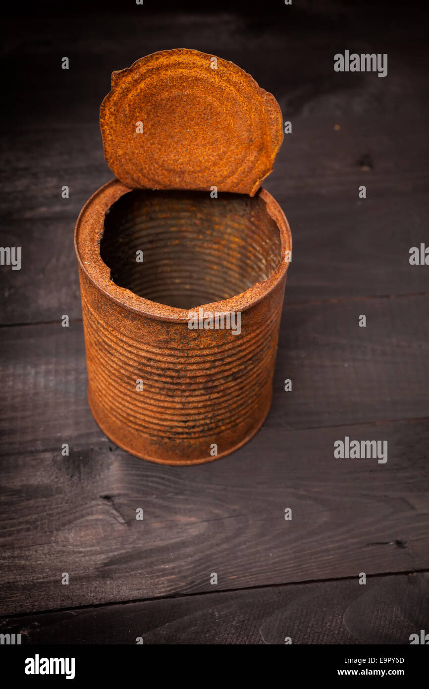 Old rusty tin can on dark wooden background Stock Photo - Alamy