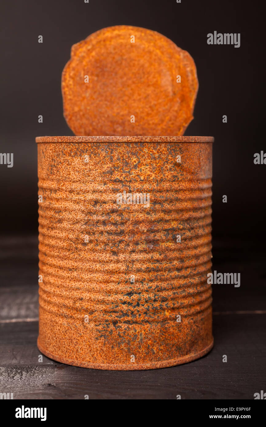 Old rusty tin can on dark wooden background Stock Photo - Alamy