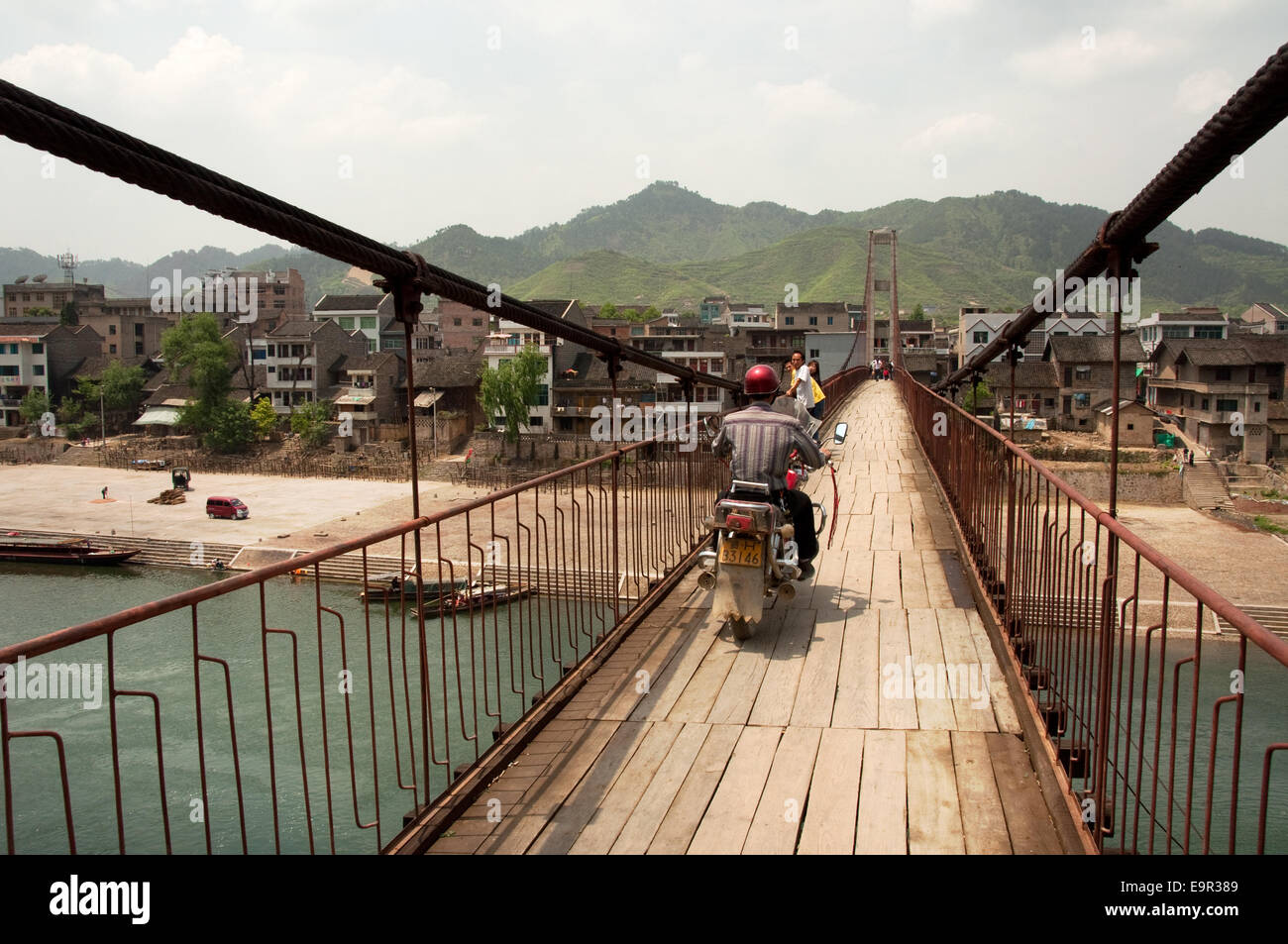 A man driving a motorcycle crossing a pedestrian bridge, Shidong ...