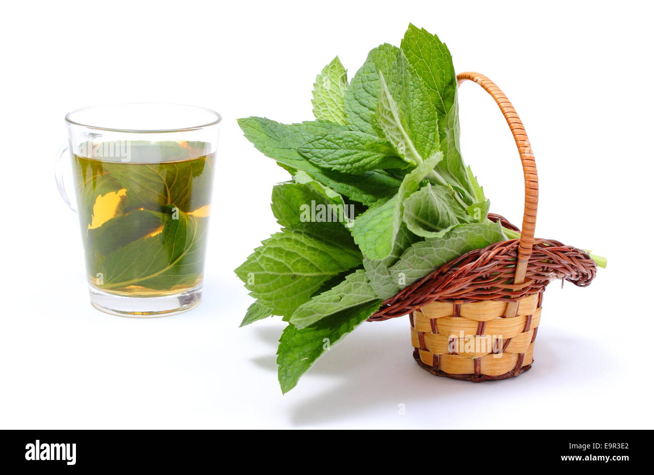 Bunch of fresh natural green mint in wicker basket and cup of brewed ...