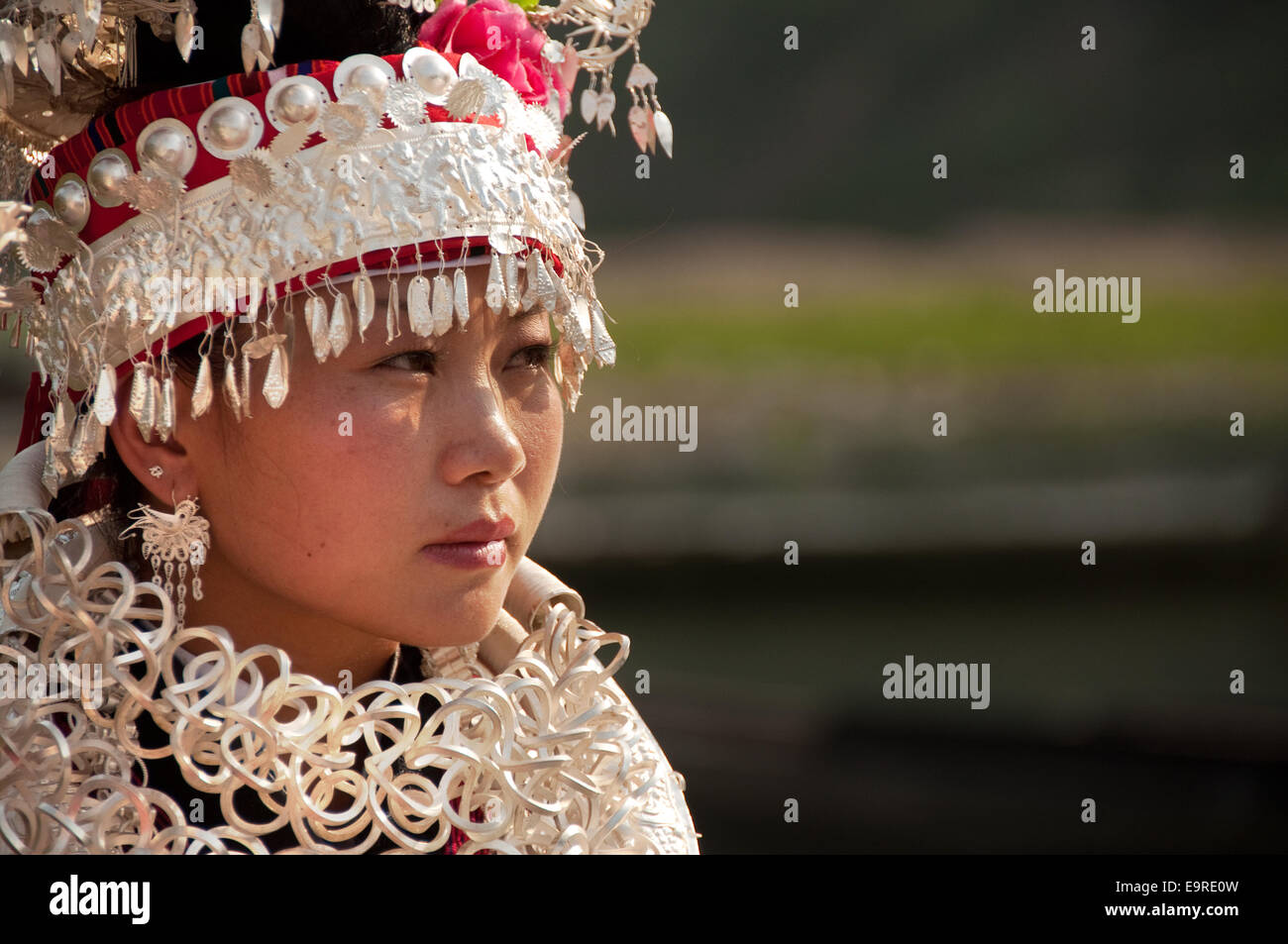 A Miao girl with traditional wear and silver jewels in front of ...