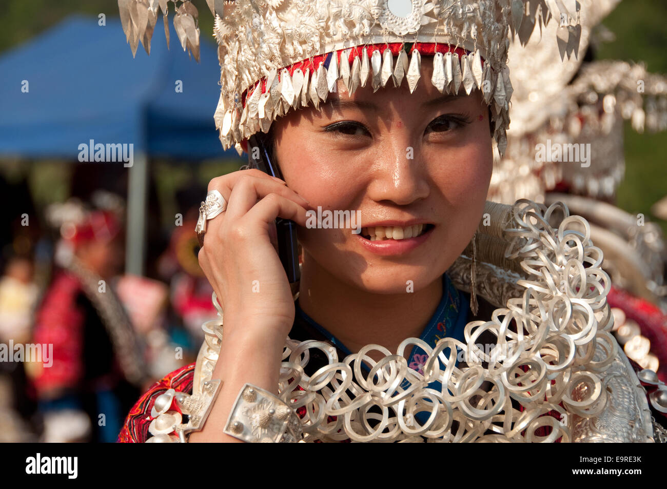 A Miao girl with traditional wear and silver jewels talking at her ...