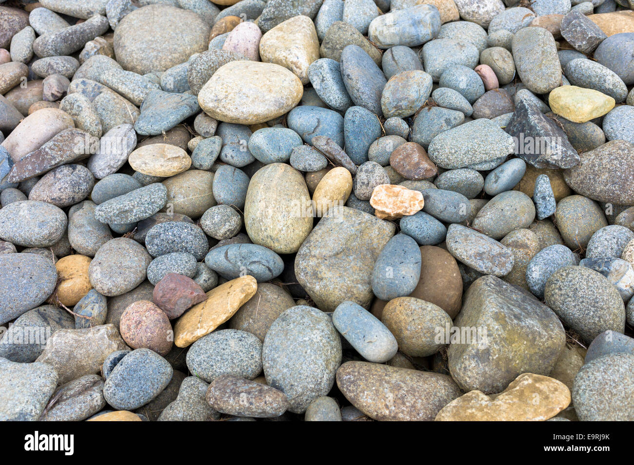 Pastel shades and various sizes of granite rocks and pebbles on beach ...