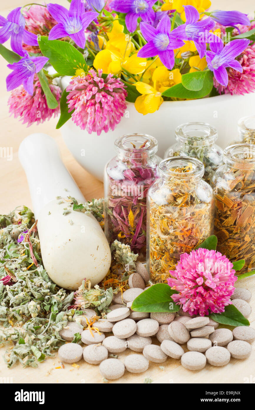 different healing herbs in glass bottles, flowers bouquet in mortar ...