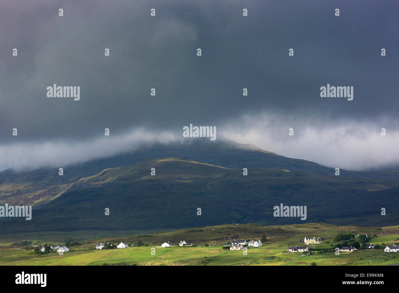 White croft cottages nestled under a mountain and grey clouds near ...