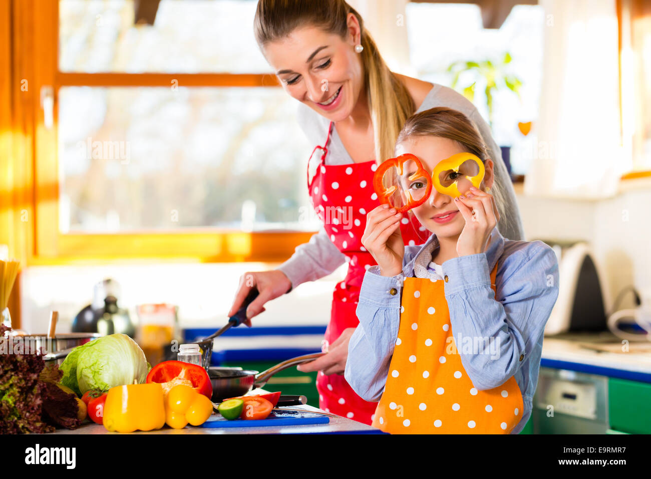 Mother and daughter cooking in domestic kitchen having fun together ...