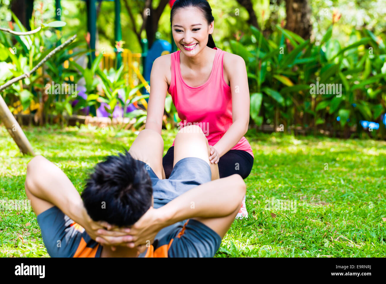 Asian Chinese woman helping man with stretching exercises in park for ...