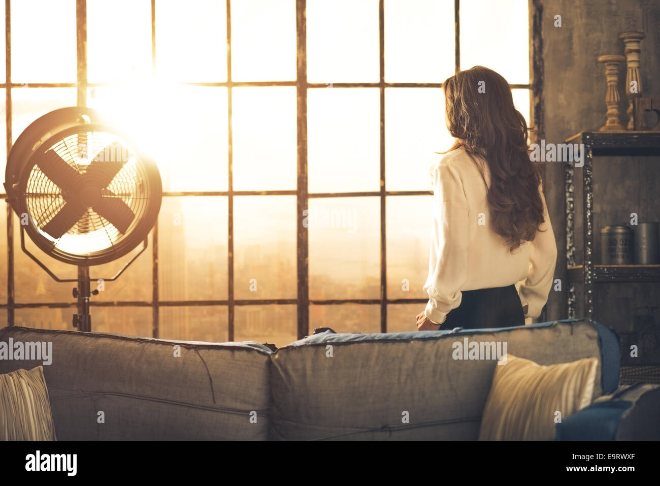 Young woman looking in window in loft apartment. rear view Stock Photo ...