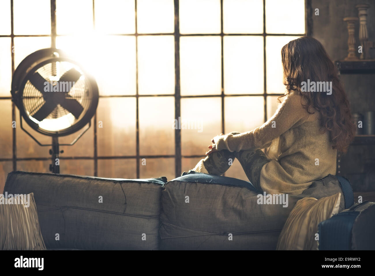 Young woman looking in window in loft apartment. rear view Stock Photo ...